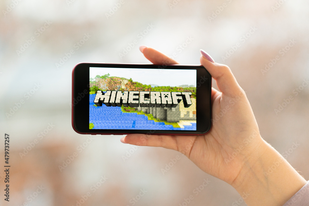 Hands holding a smartphone with Minecraft Pocket Edition game on ...