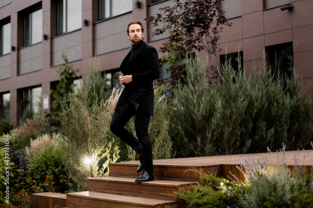 Stylish dressed businessman is walking down by stairs, looking at the ...