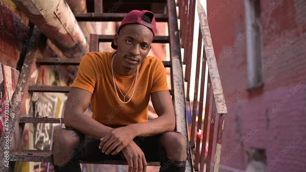 Vidéo Stock The camera zooms in on a young black guy sitting on a ...