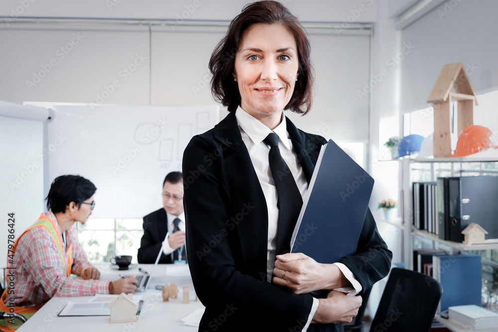 Confident beautiful middle aged business woman in black suit holding ...