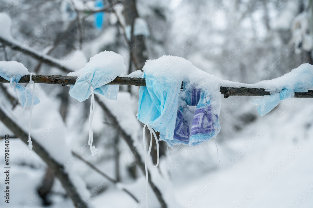 Surgical masks on trees in winter forest. Consequences of overuse of ...