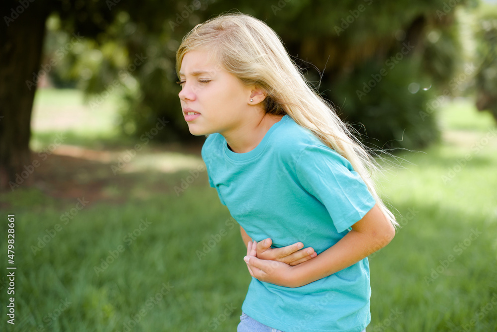 Caucasian little kid girl wearing blue T-shirt standing outdoors with ...