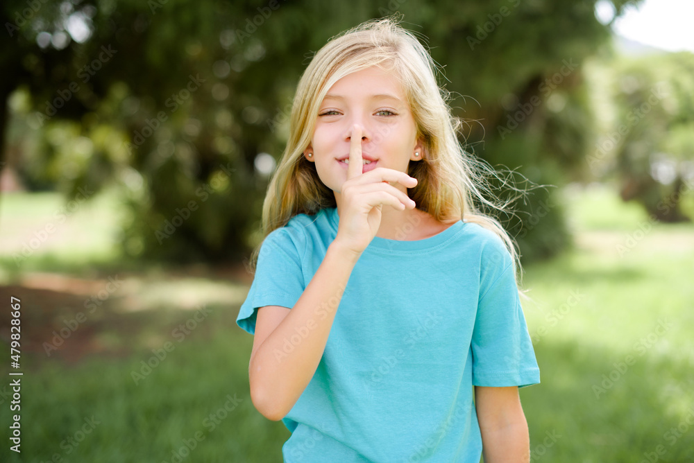 Caucasian little kid girl wearing blue T-shirt standing outdoors makes ...