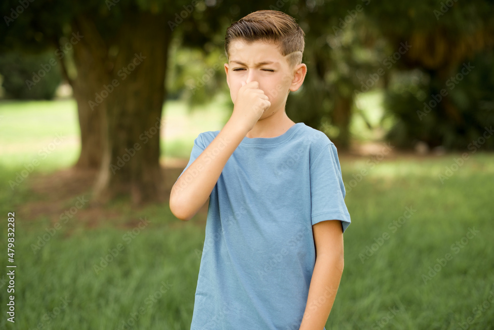 Caucasian little kid boy wearing blue T-shirt standing outdoor smelling ...