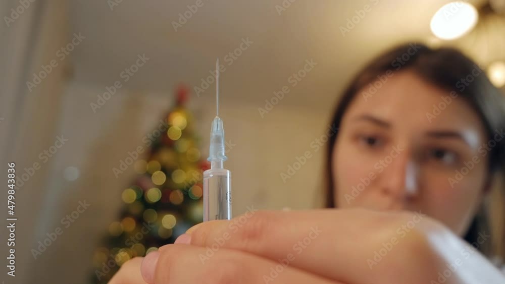 A young woman, at home, prepares a pre-filled syringe for injection by ...