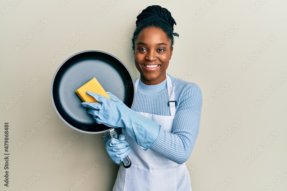 African american woman with braided hair wearing apron holding scourer ...