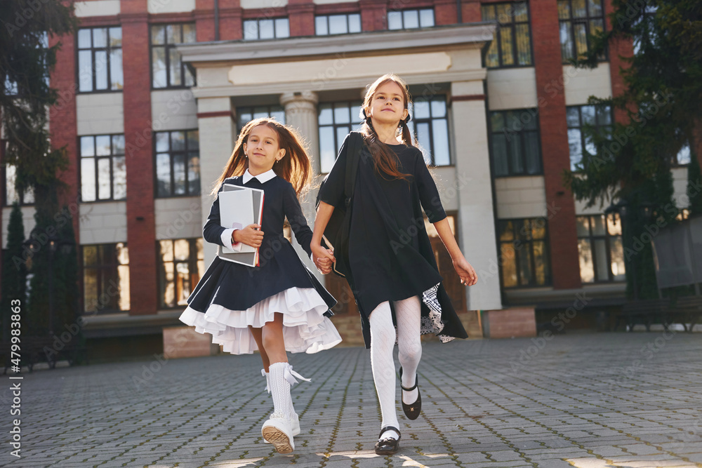 Two schoolgirls is running outside together near school building Stock ...