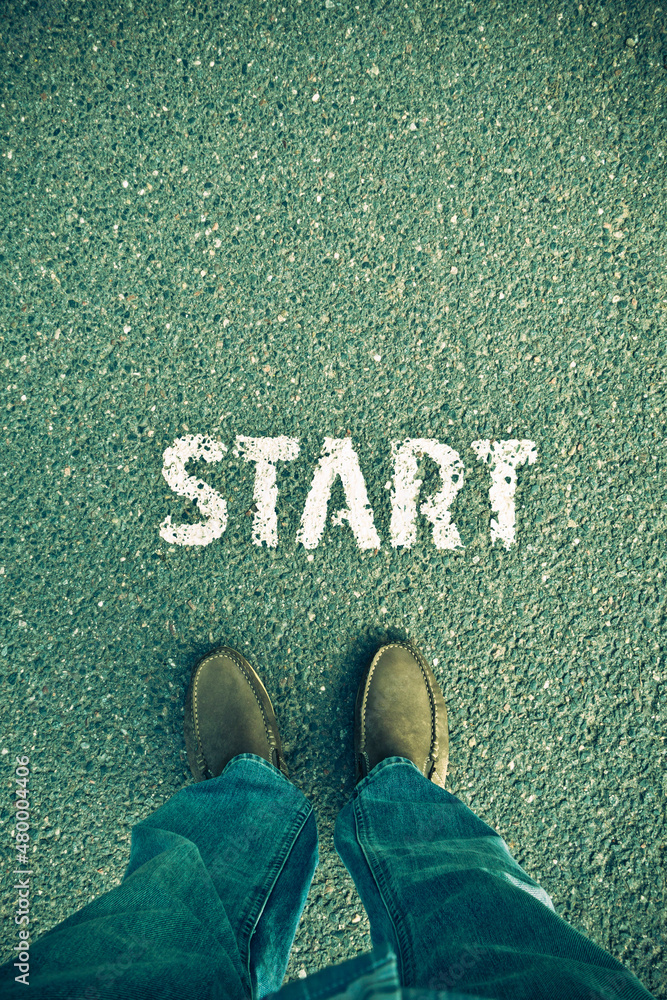 feet and legs of a man standing near the word START, conceptual image ...
