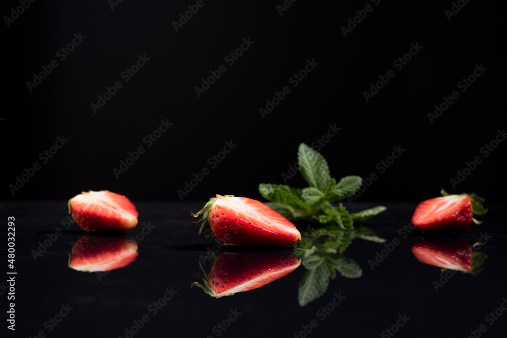 Foto de Tres fresas partidas por la mitad aisladas sobre agua con hojas ...