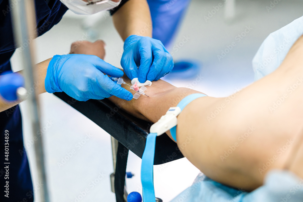 The doctor's hands in gloves stick a dropper needle into the patient's ...