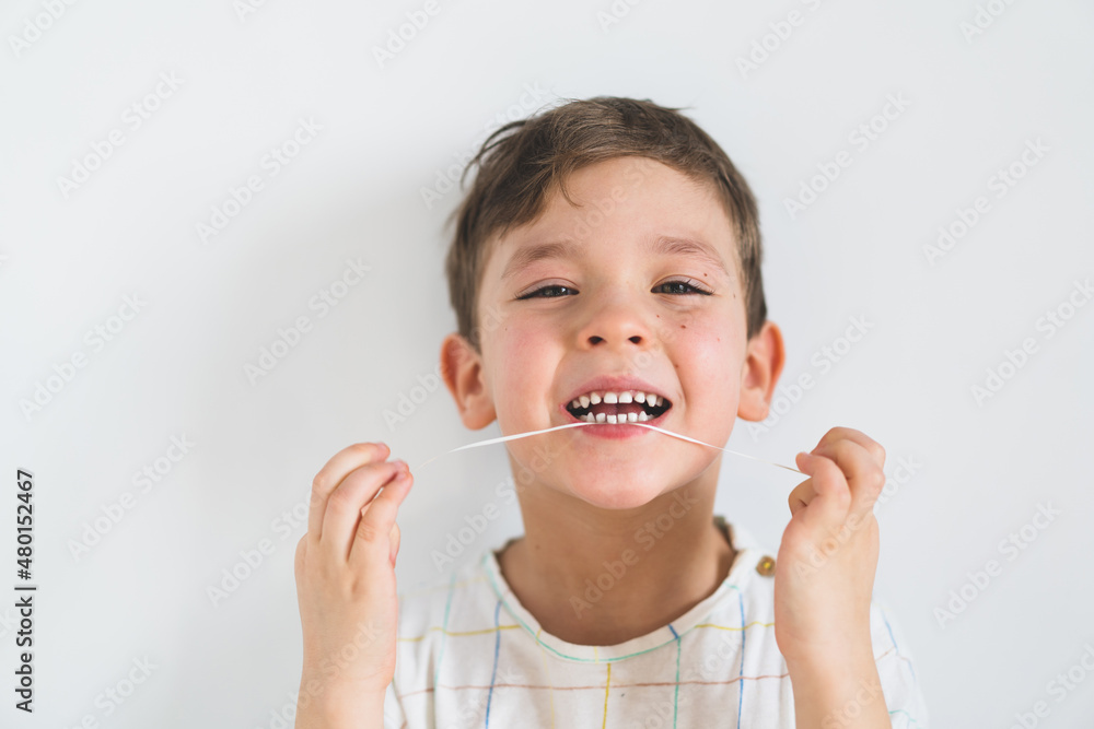 Naklejka Cute boy pulling loose tooth using a dental floss. The boy's ...