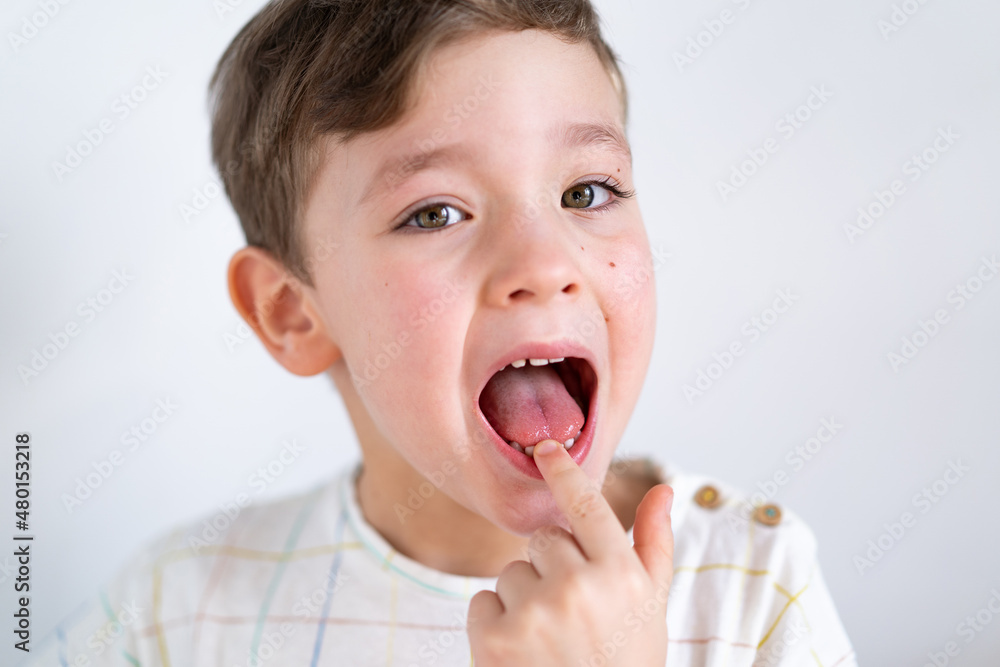 Cute boy pulling loose tooth. The boy's first milk tooth is loose ...