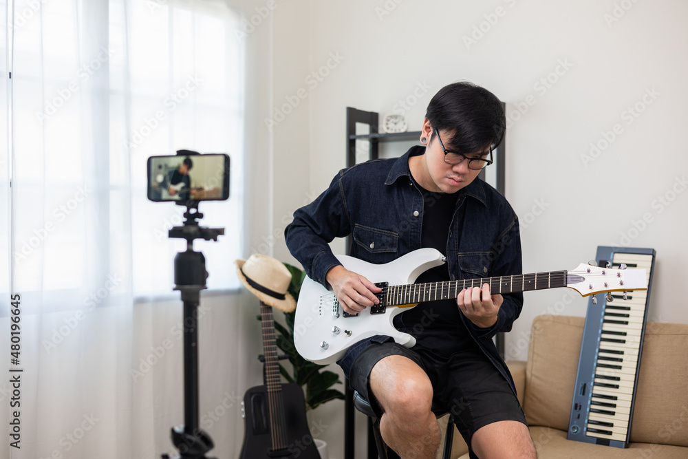 Young asian musician teaching the rock guitar class online live ...