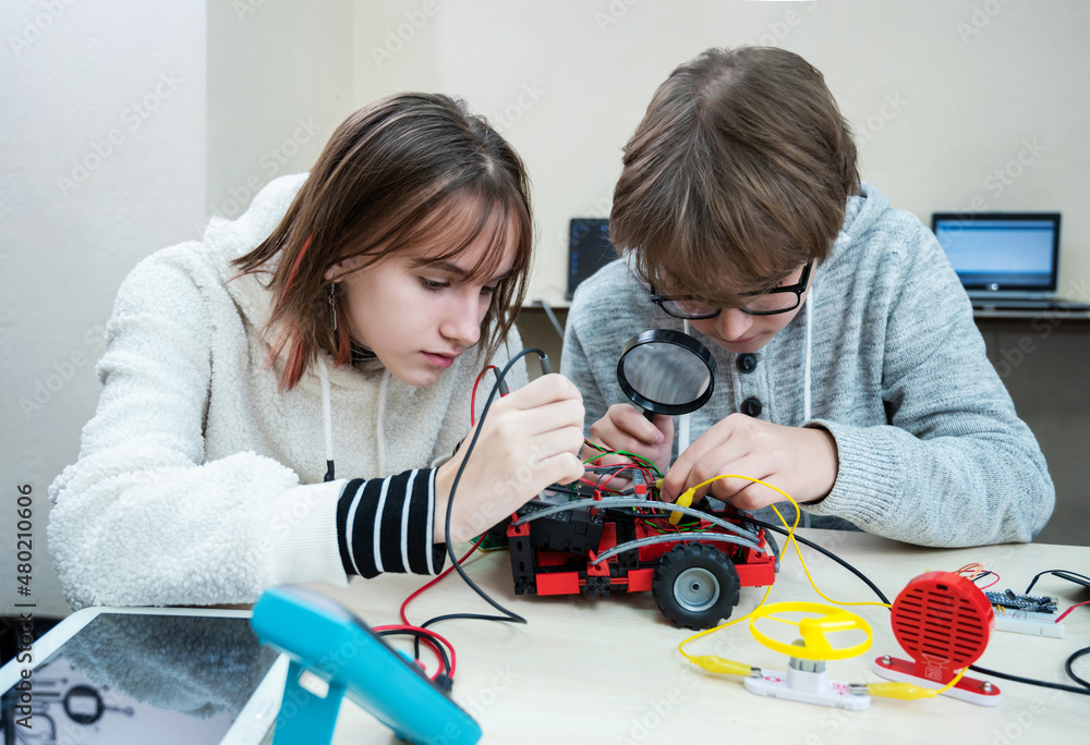 School student making robotic cars. Teenager girl and boy at robotics ...