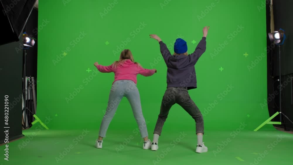 Two girls dancing . Young women in casual clothes having fun over green ...