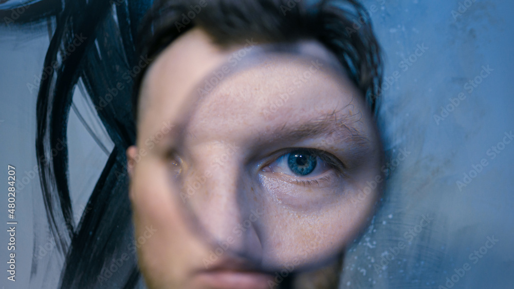 Human eye through a magnifying glass. Young man looking through a ...