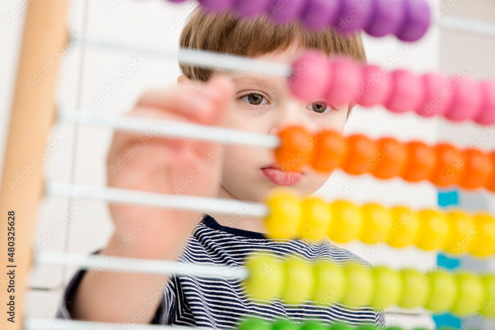 A cute kid is playing with an abacus at home. A smart child learns to ...