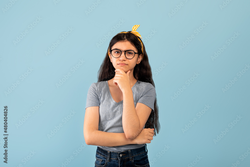 Thoughtful Indian teen girl in glasses remembering something, touching ...