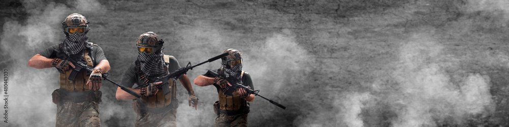 Three military mercenaries walk against a concrete wall background and ...