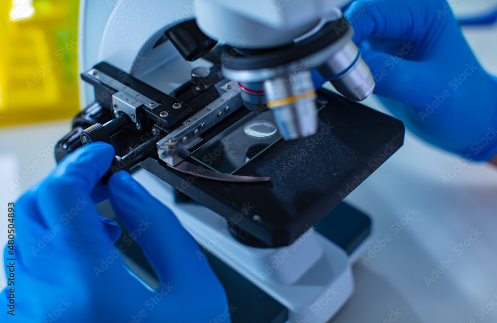 Closeup shot of microbiology defective sample on glass plate placing under microscope zooming ...