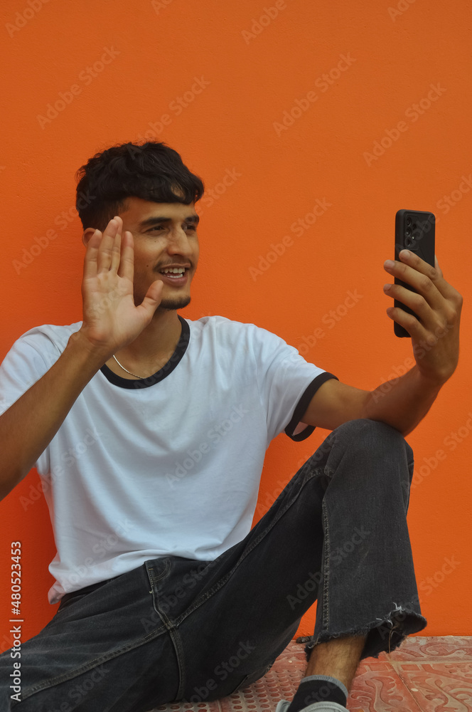 A happy young guy saying hello with waving his hand to someone while ...