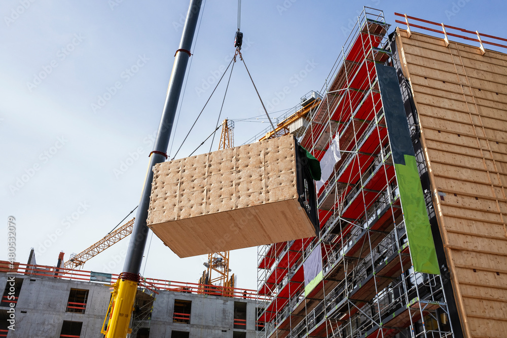 Crane lifting a wooden building module to its position in the structure ...