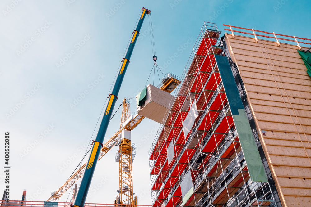 Crane lifting a wooden building module to its position in the structure ...