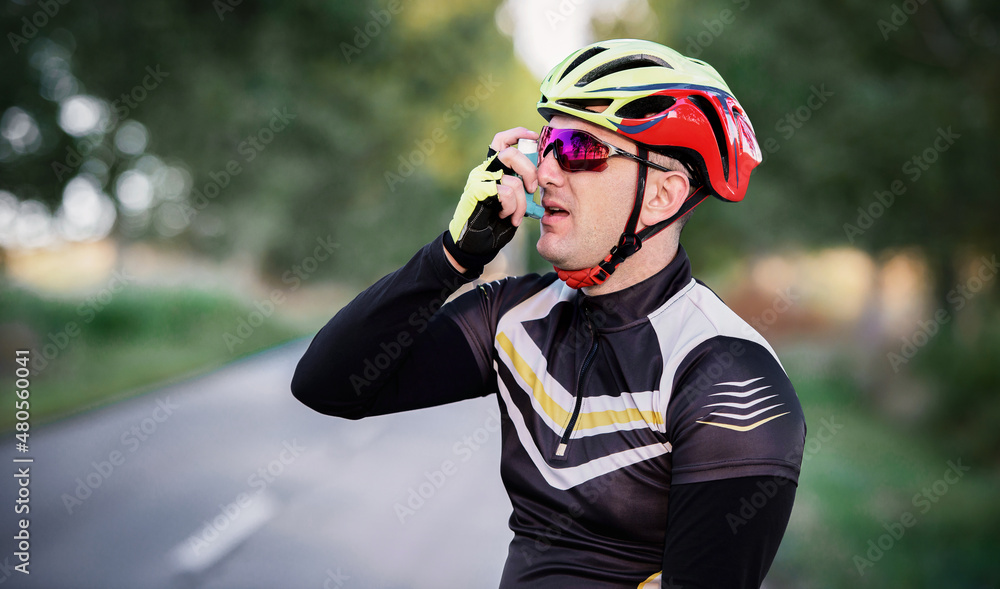 Sports and asthma. Cyclist using asthma inhaler. Sport and recreation ...