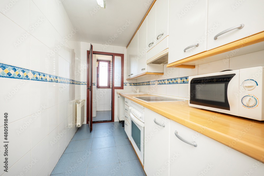 Furnished kitchen on one side of the room with white furniture and ...