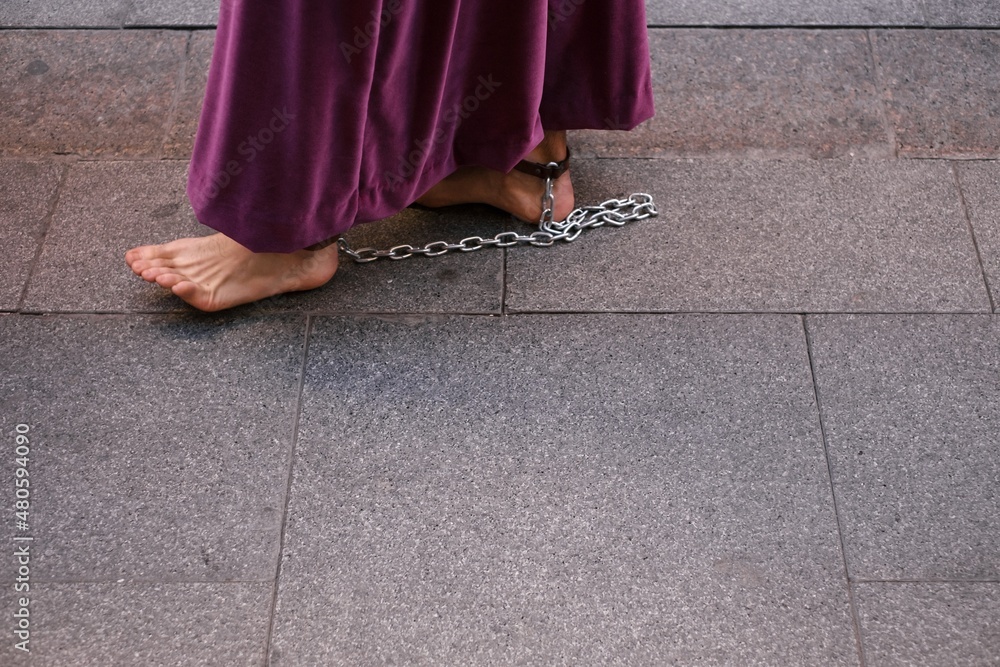 Feet of a barefoot man walking in chains through the streets of the ...