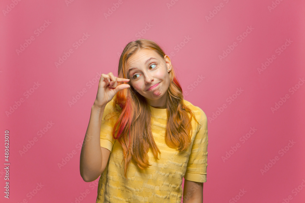 Cute young girl look at hand showing with fingers something small with ...