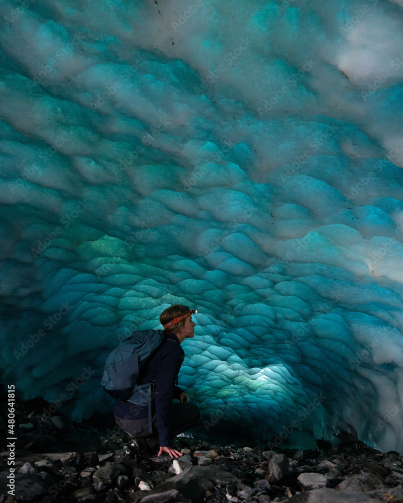 Adventurous Ice Climber Woman walking in an ice cave on a glacier in ...