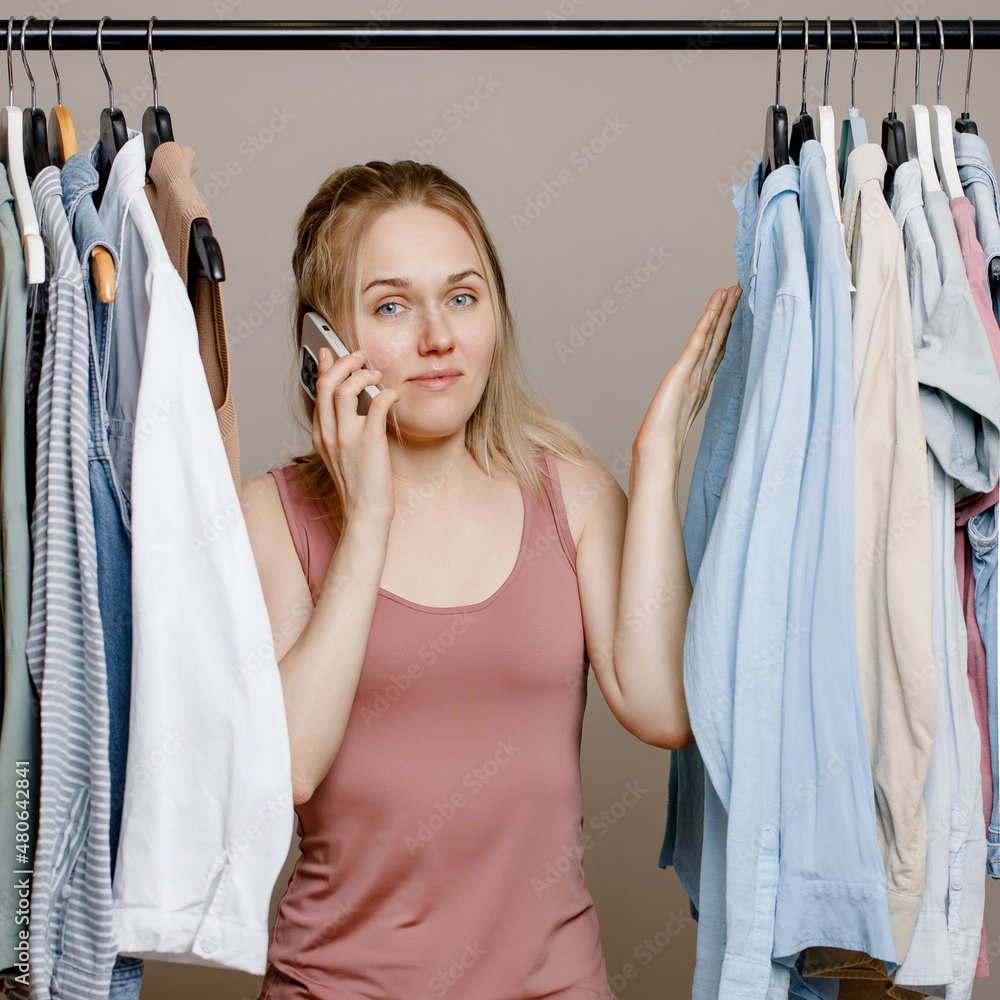 Pretty white woman shrugs her shoulders, doubting what to wear ...