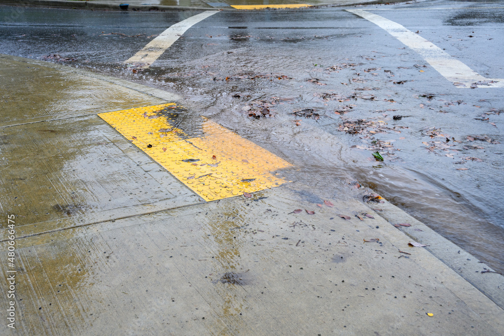 Flooding from heavy rains running down a sidewalk, access ramp ...