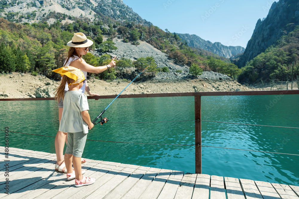 Mother teaching her daughter how to catch a fish at summer day. Family ...