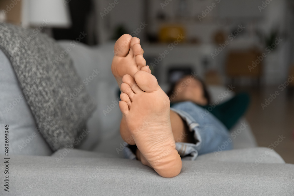 Close up focus on bare feet of relaxed young female homeowner fallen ...