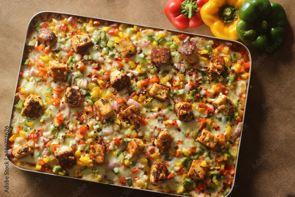 Home baked pizza loaded with paneer, mozzarella cheese, red yellow ...