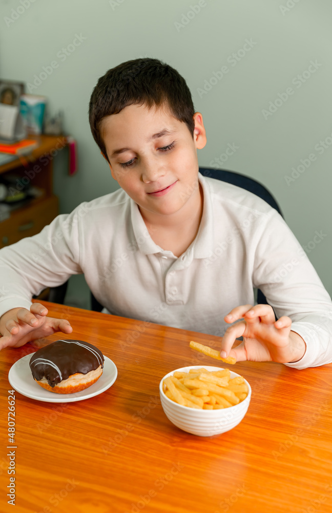 Diet or healthy lifestyle concept. Happy boy eating a french fries ...