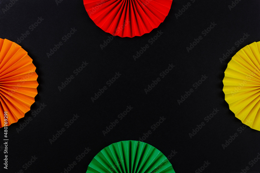 Red, orange, yellow and green color paper origami flowers on the black ...