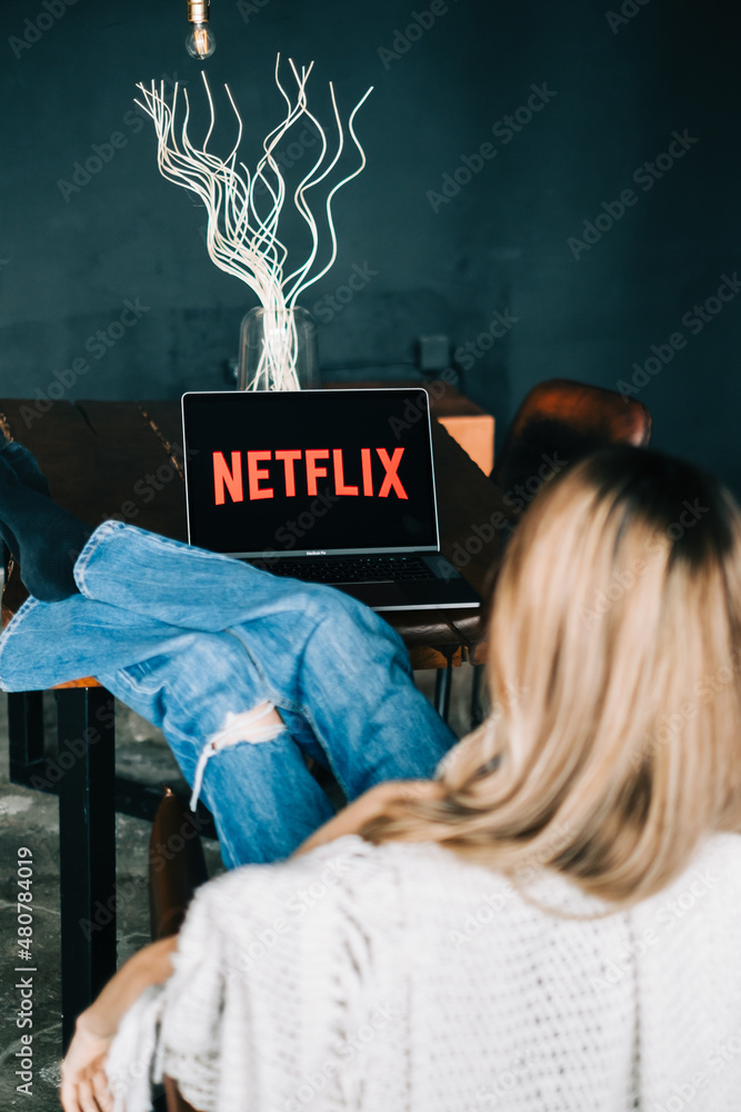 Netflix logo on the laptop screen. Young woman watching netflix channel ...