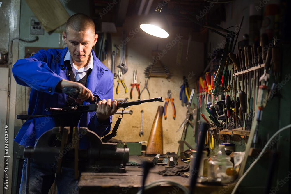 Foto de Gunsmith with Kalashnikov assault rifle in a weapons workshop ...