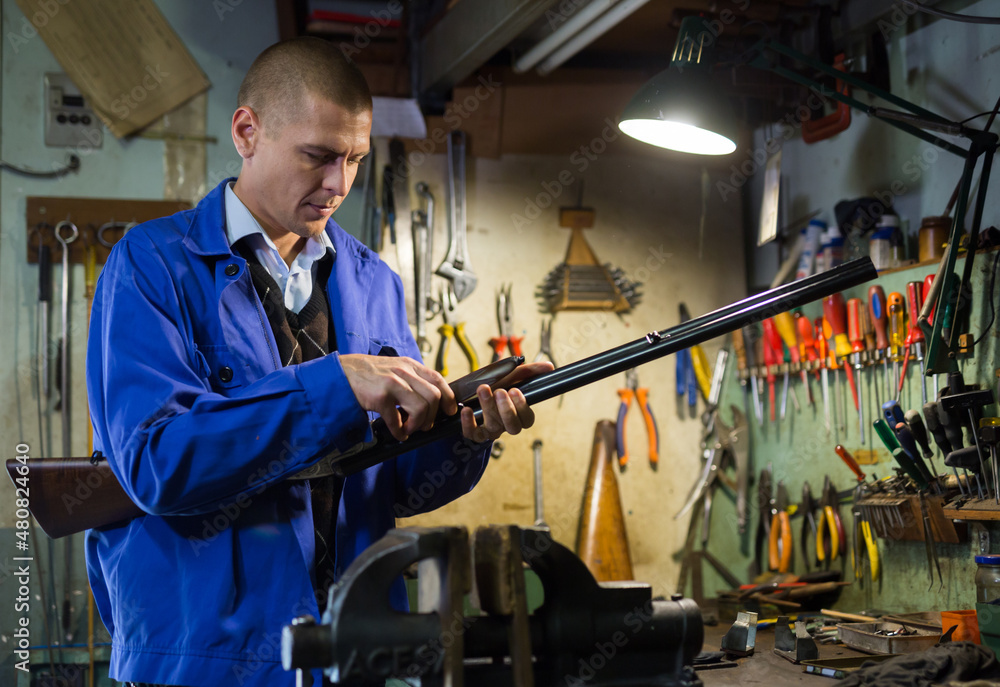 Gunsmith examines and checks double-barreled hunting rifle in a weapons ...