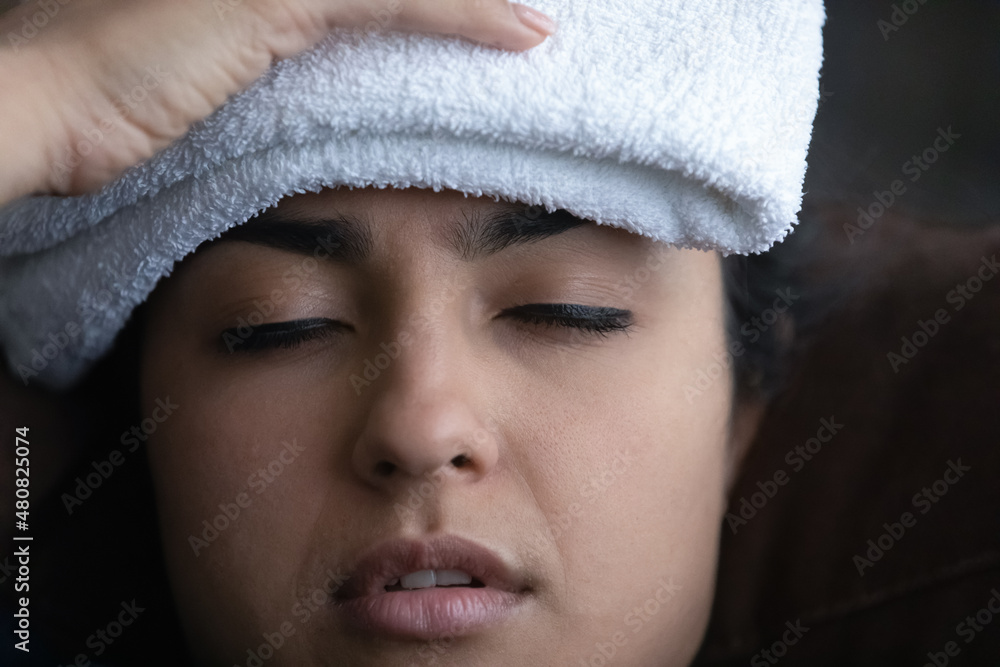 Close up head shot unhealthy young Indian woman holding cold towel ...