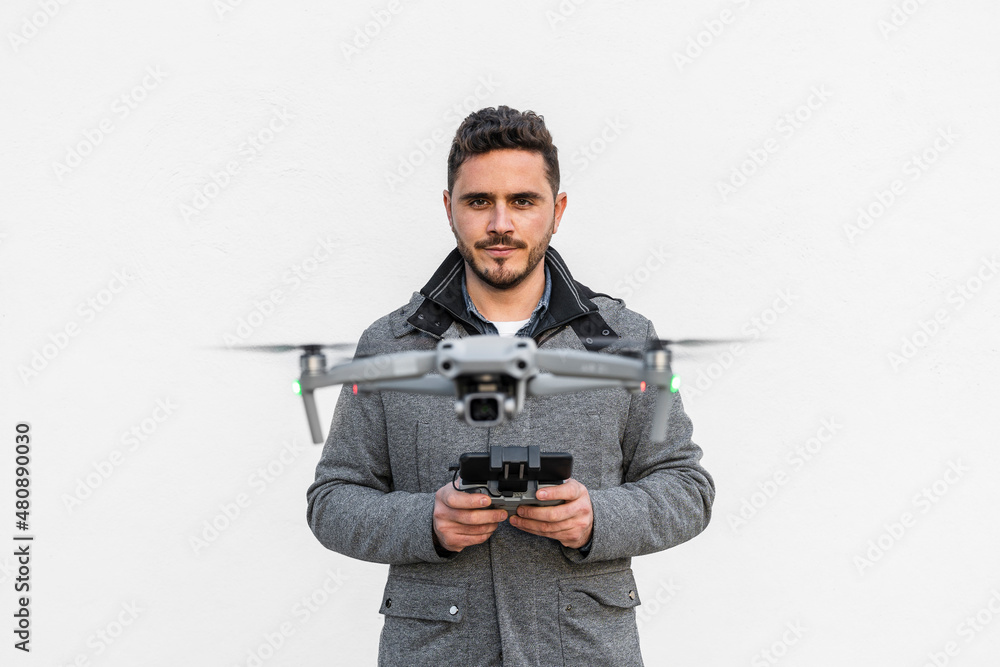 Confident man flying drone against white background Stock Photo | Adobe ...