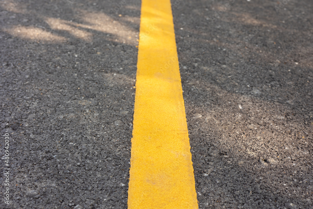 Close up yellow line on concrete road with rough surface under sunlight ...