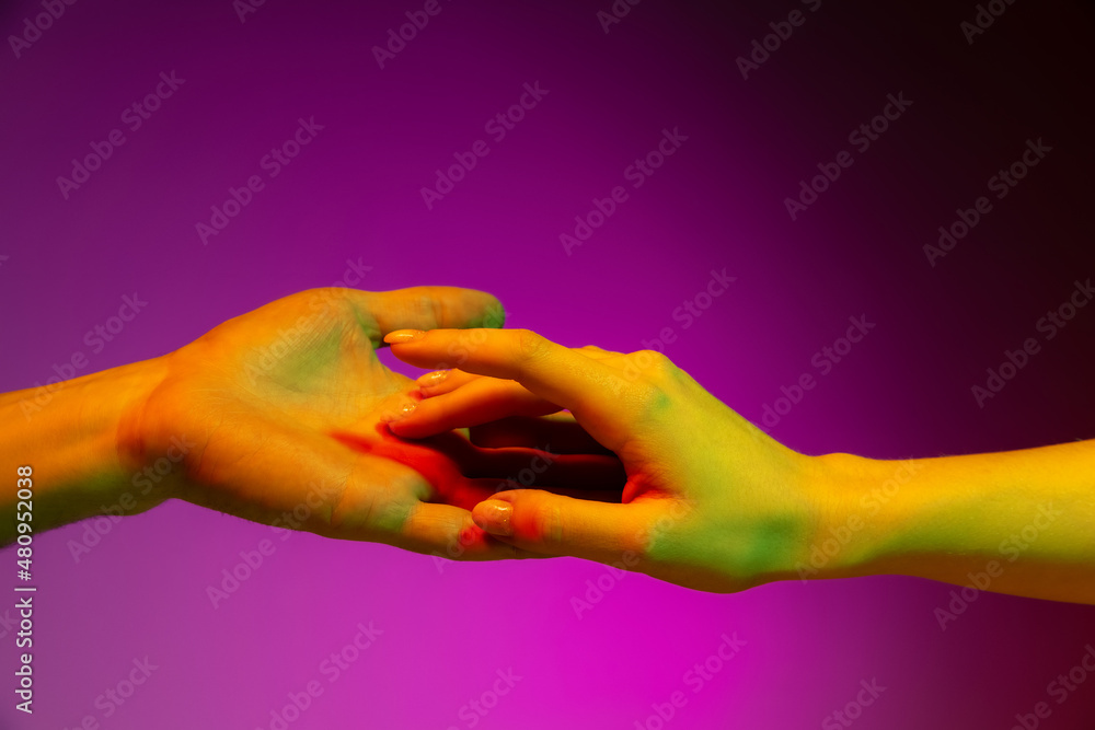 Two human hands trying to touch each other isolated on purple studio ...