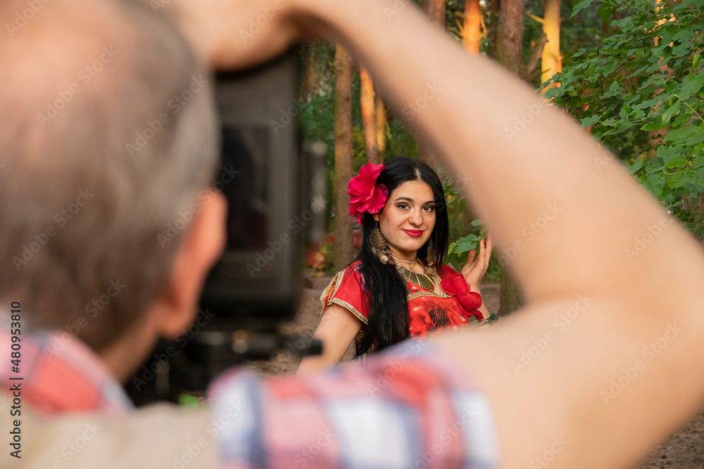 A professional photographer photographs a gypsy girl model in a red ...
