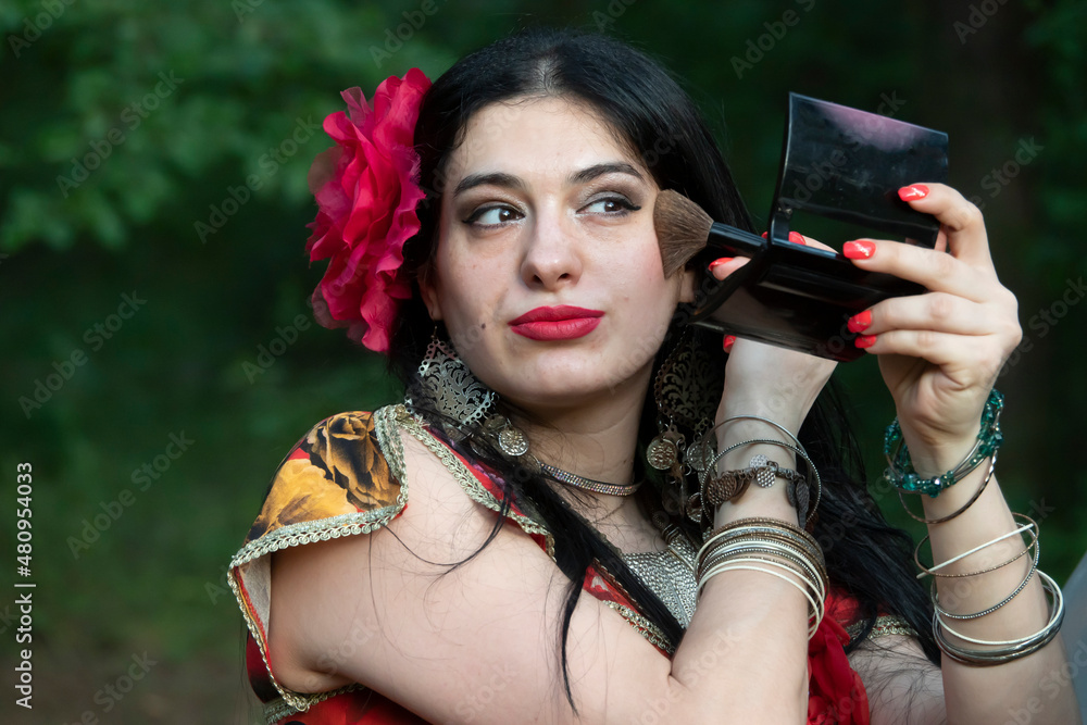 A gypsy woman applies makeup. Powdery blush. Portrait of a girl in an ...