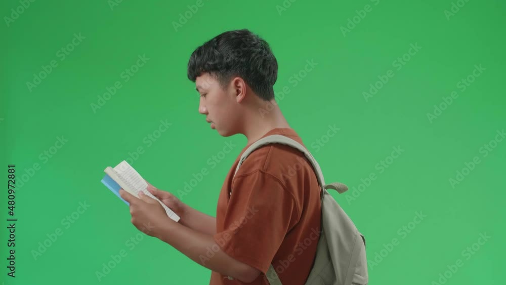 The Side View Of Asian Boy Student Holding And Reading Book While ...
