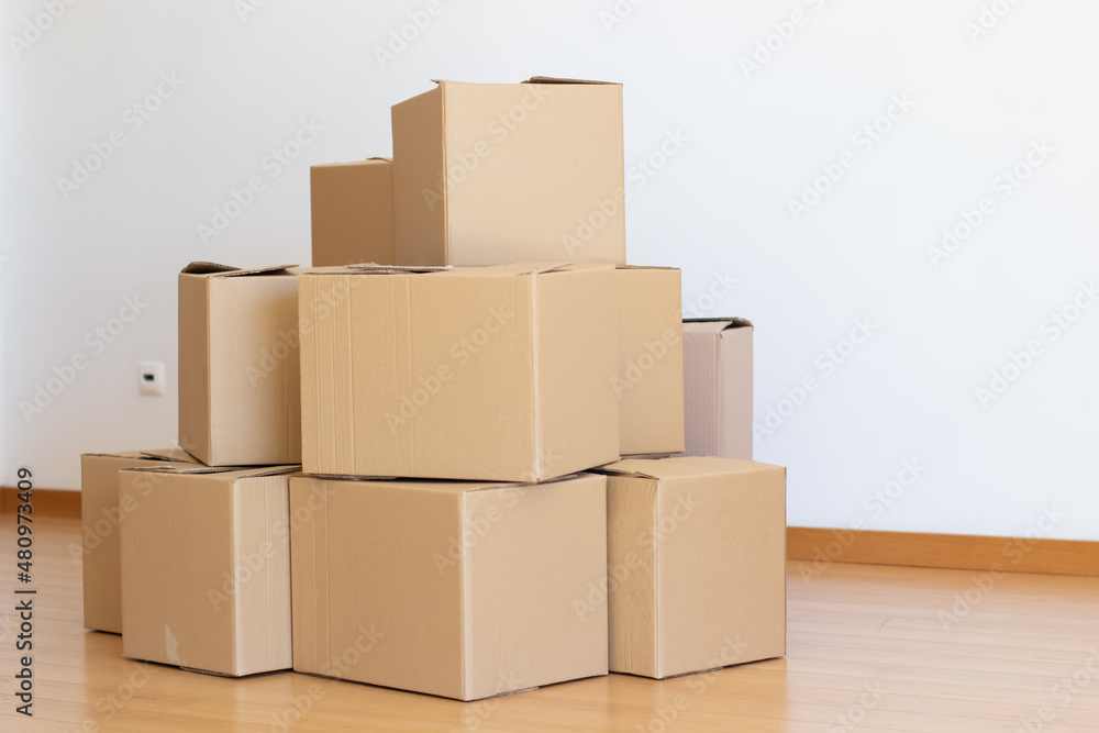 Stack of cardboard boxes in empty room. Packed things ready for moving ...